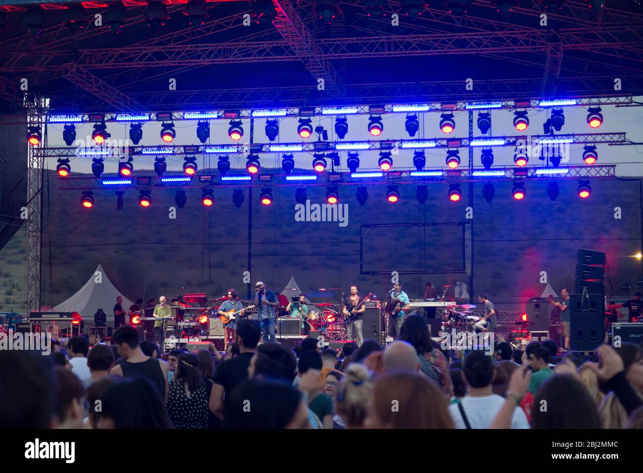 Audience with hands raised at a music festival and lights streaming ...