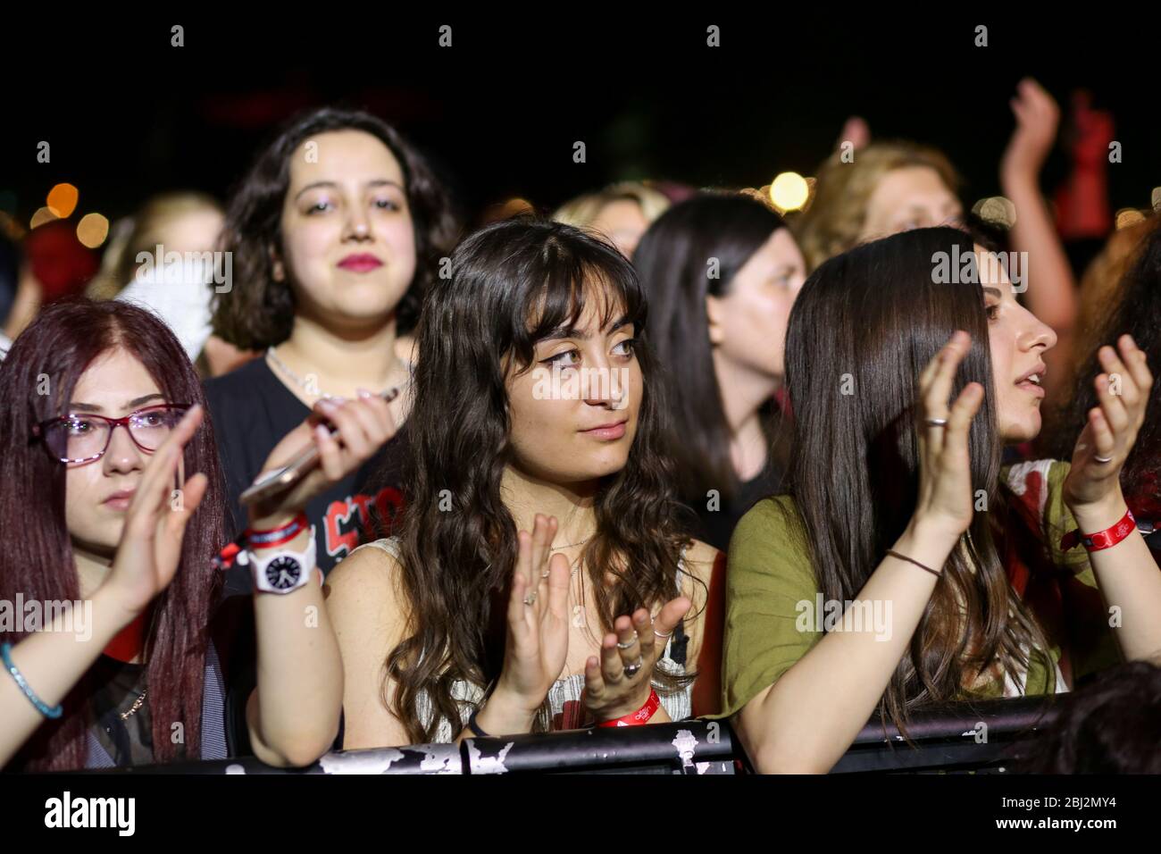 Audience with hands raised at a music festival and lights streaming ...