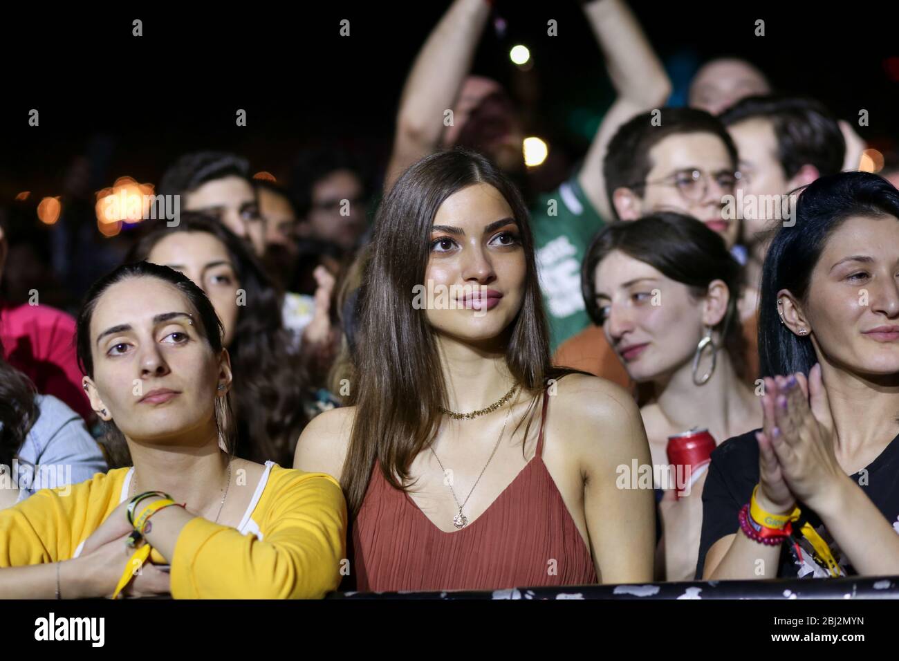 Audience with hands raised at a music festival and lights streaming ...