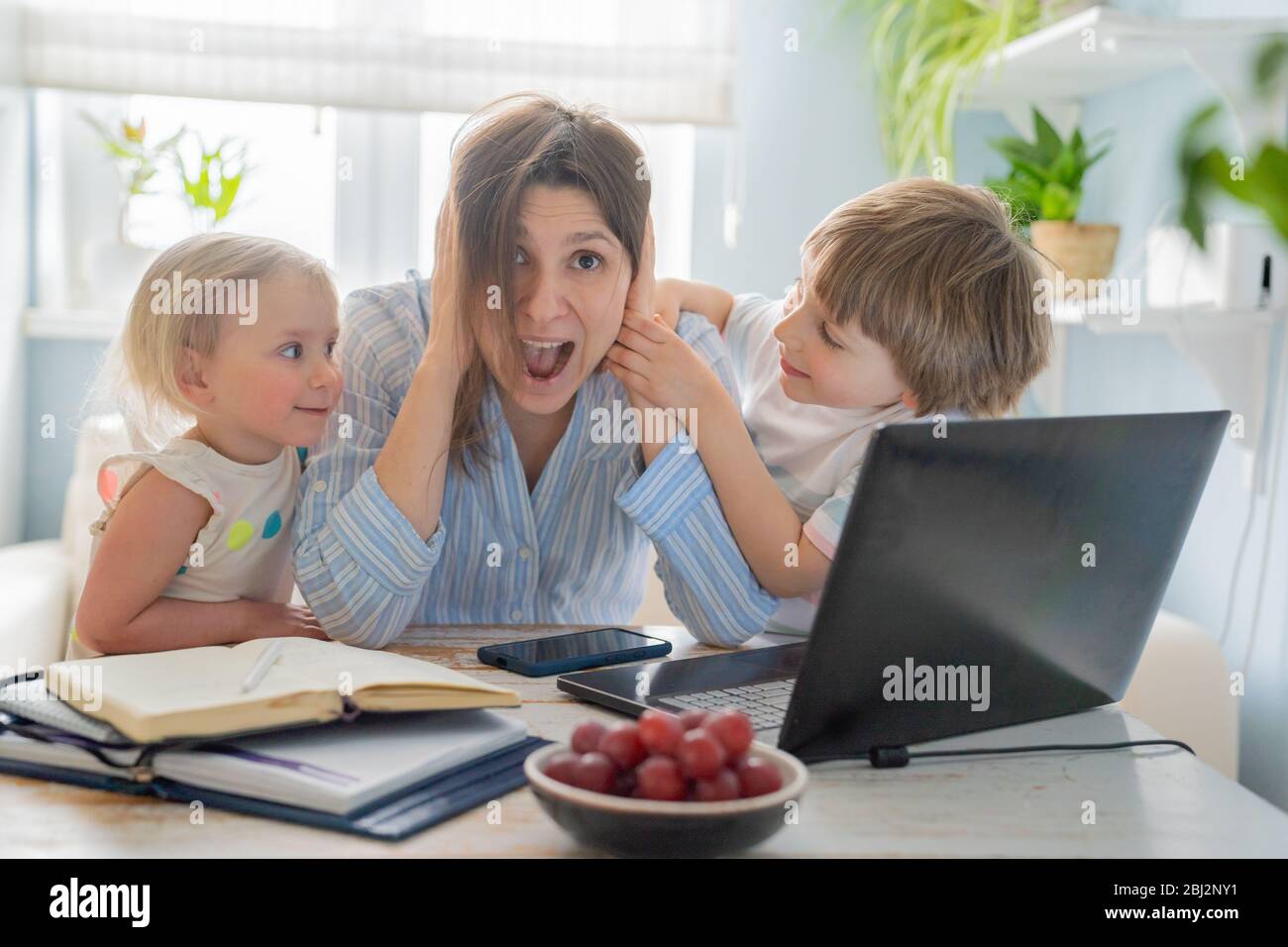 Female working from home with kids running and screaming Stock Photo ...