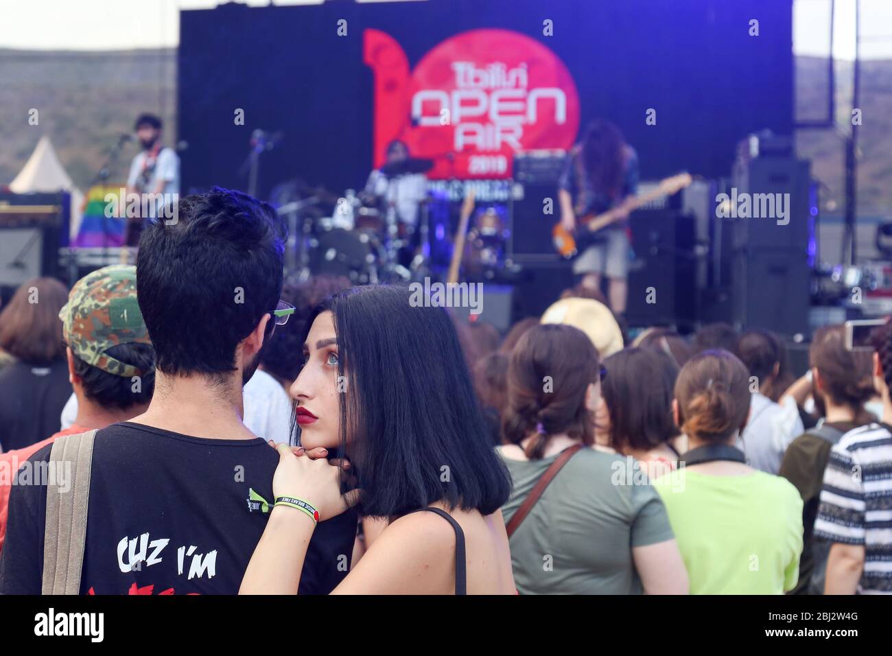 Audience with hands raised at a music festival and lights streaming ...