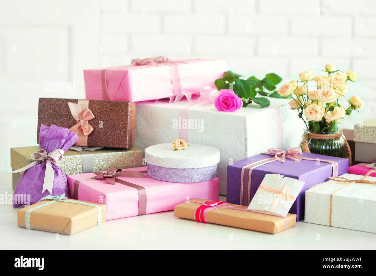 Decorated gift boxes and flowers on the table in front of white brick ...