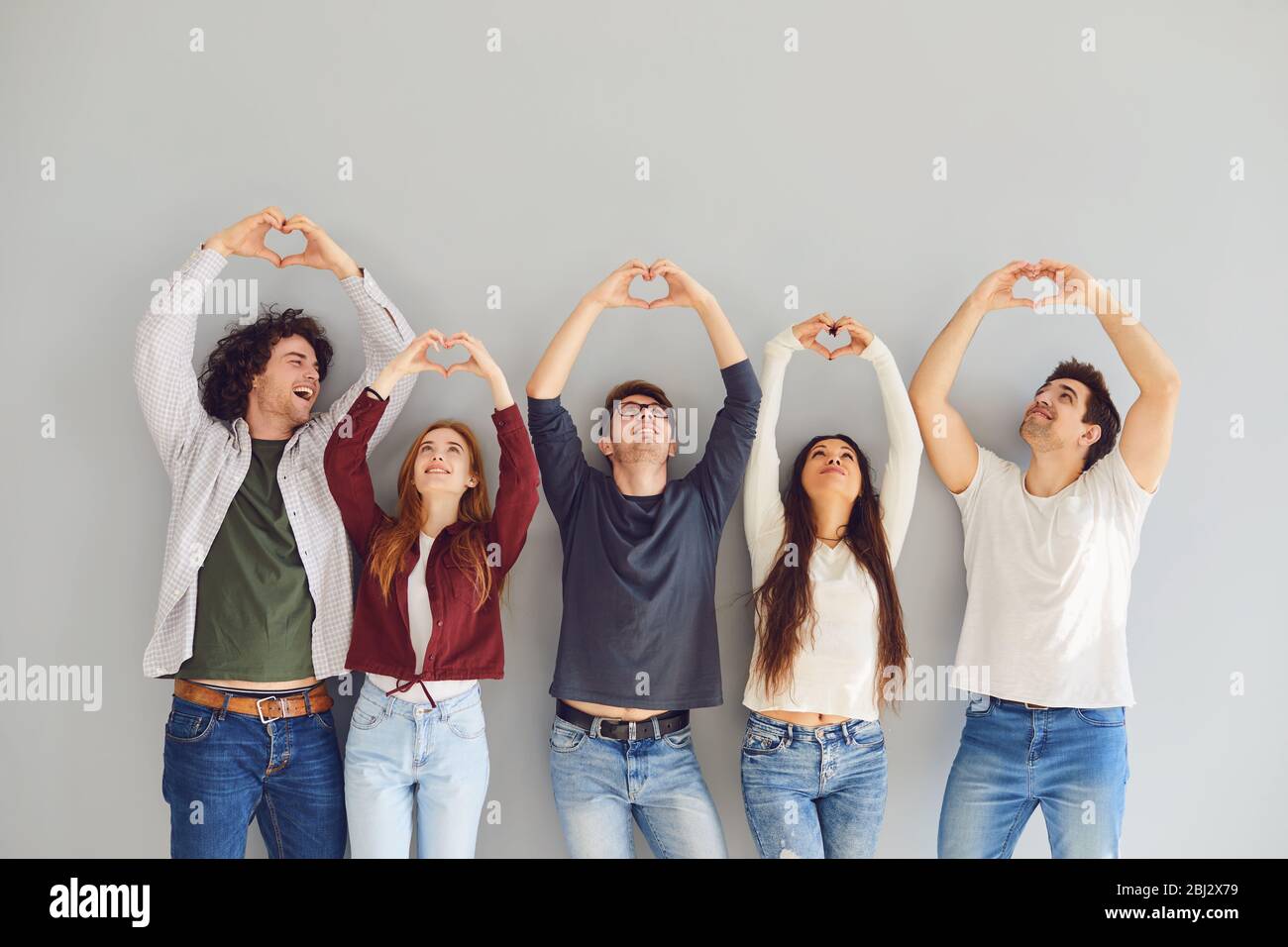 Group of friends making heart sign with hands on gray background Stock ...