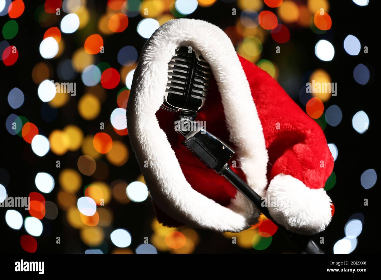 Old microphone decorated with Christmas hat against defocused lights ...