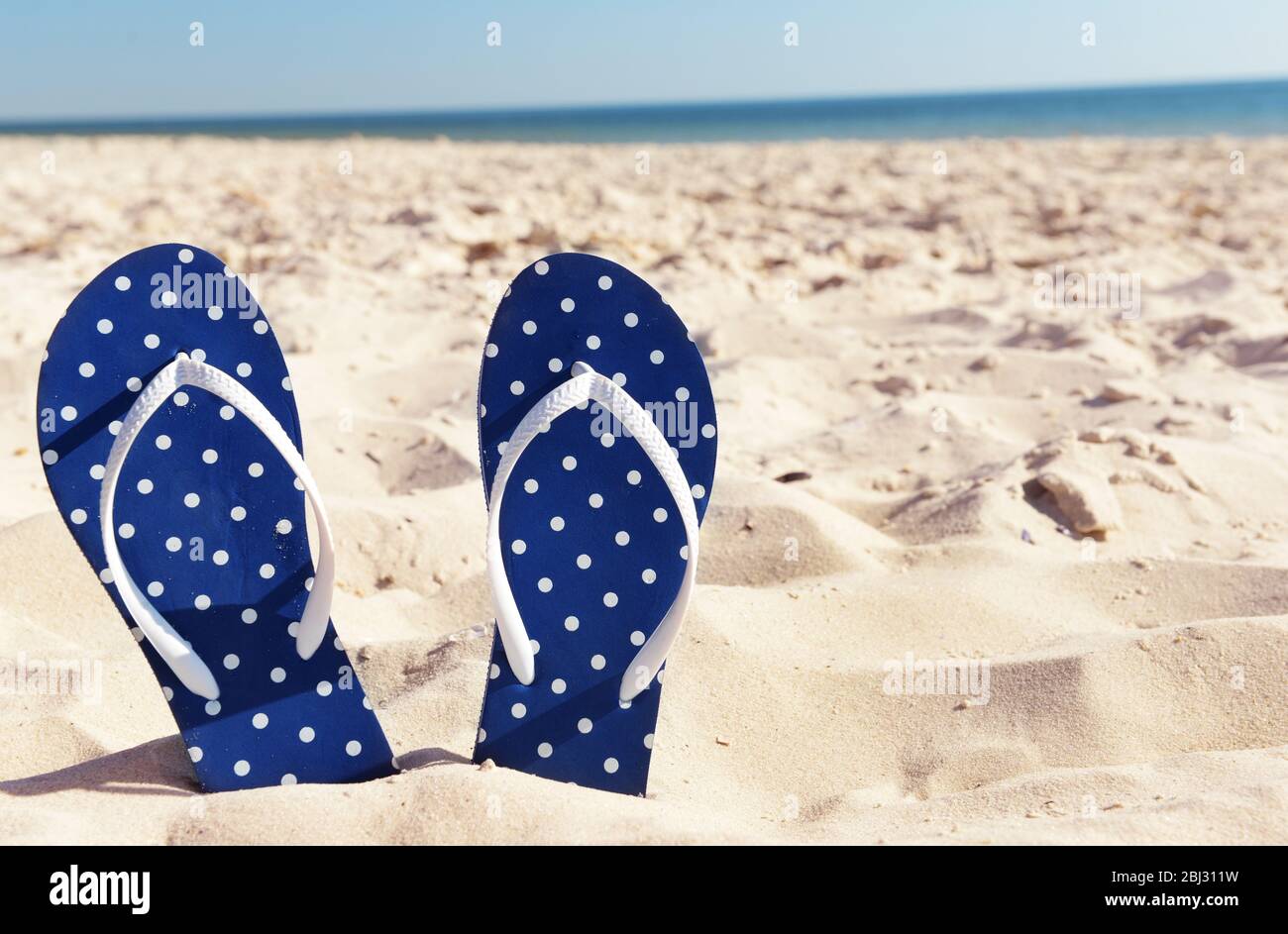 Flip flops on beach sand closeup Stock Photo - Alamy