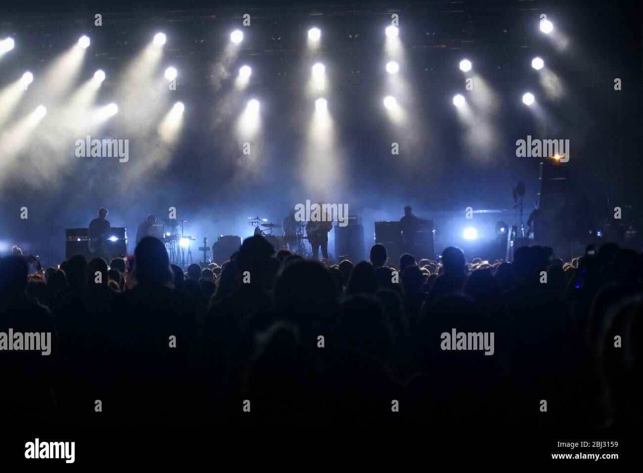 Audience with hands raised at a music festival and lights streaming ...