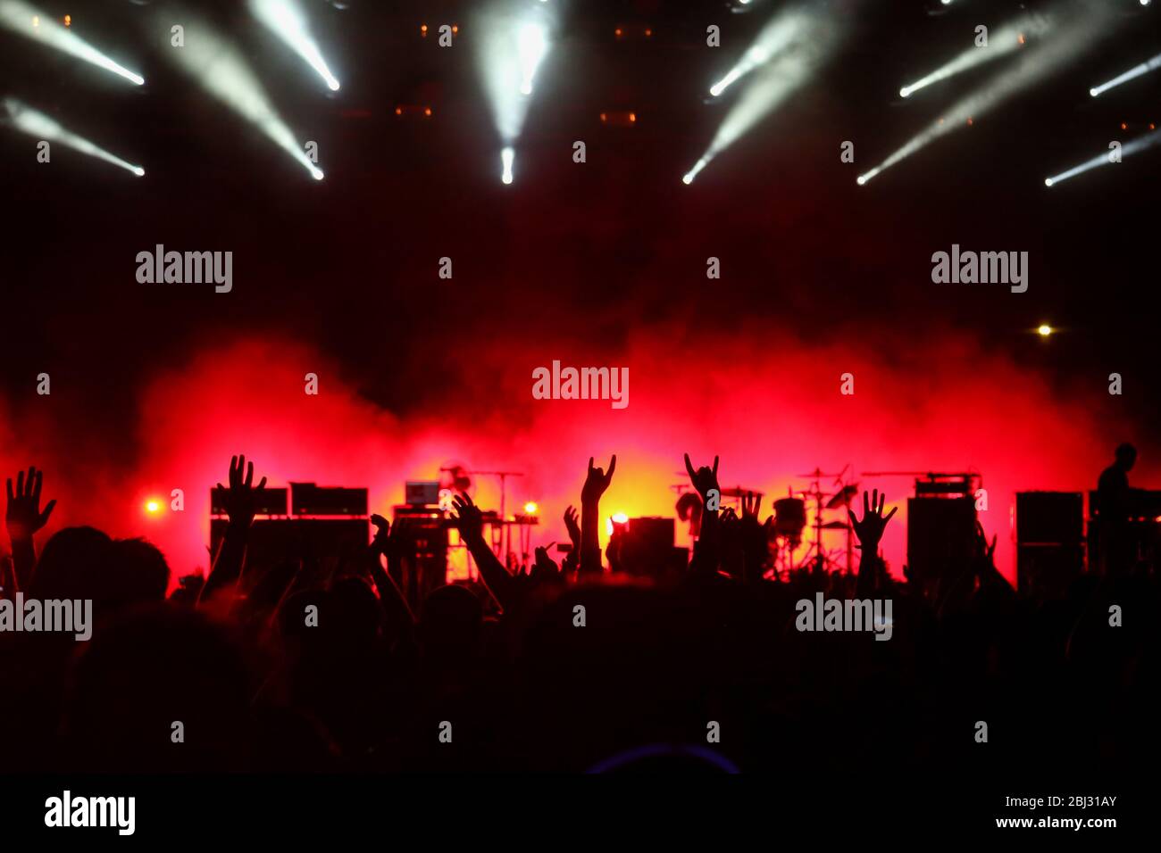 Audience with hands raised at a music festival and lights streaming ...