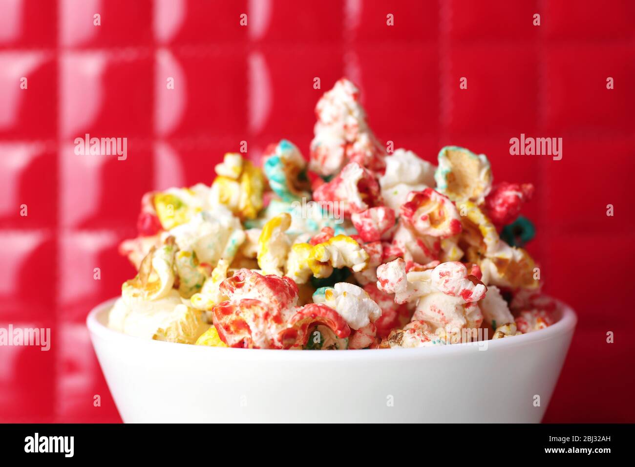 Sweet colourful popcorn on red background Stock Photo - Alamy