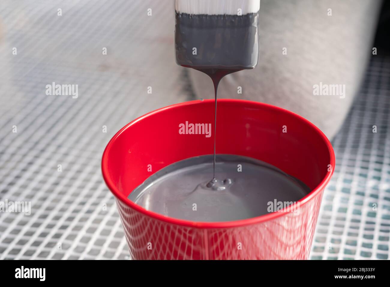 Close up of dipping brush into grey paint outside. Home renovation ...