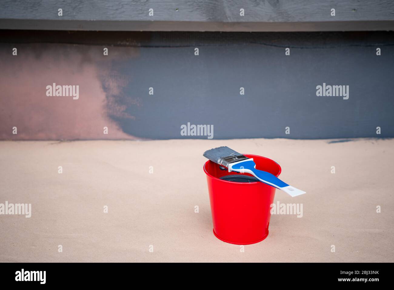 Paint brush and a bucket with paint next to a building exterior wall ...