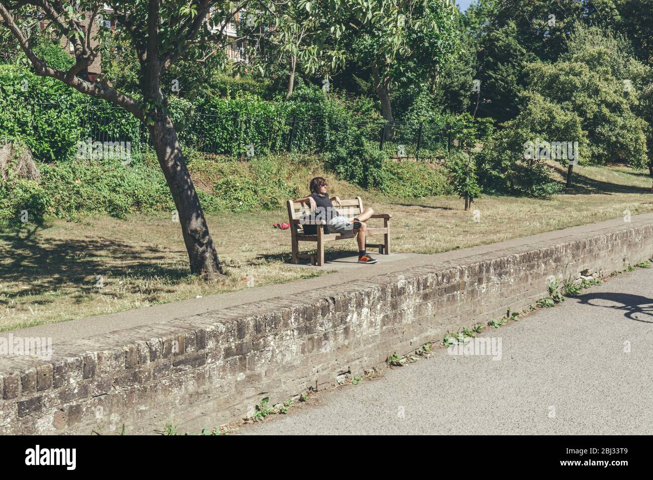 London/UK-1/08/18: a man in sunglasses, sitting alone on a bench ...