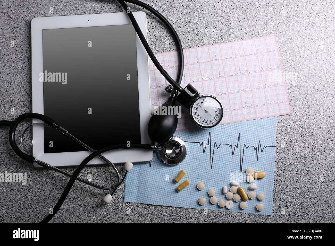 Blood pressure meter, stethoscope, digital tablet on gray background ...