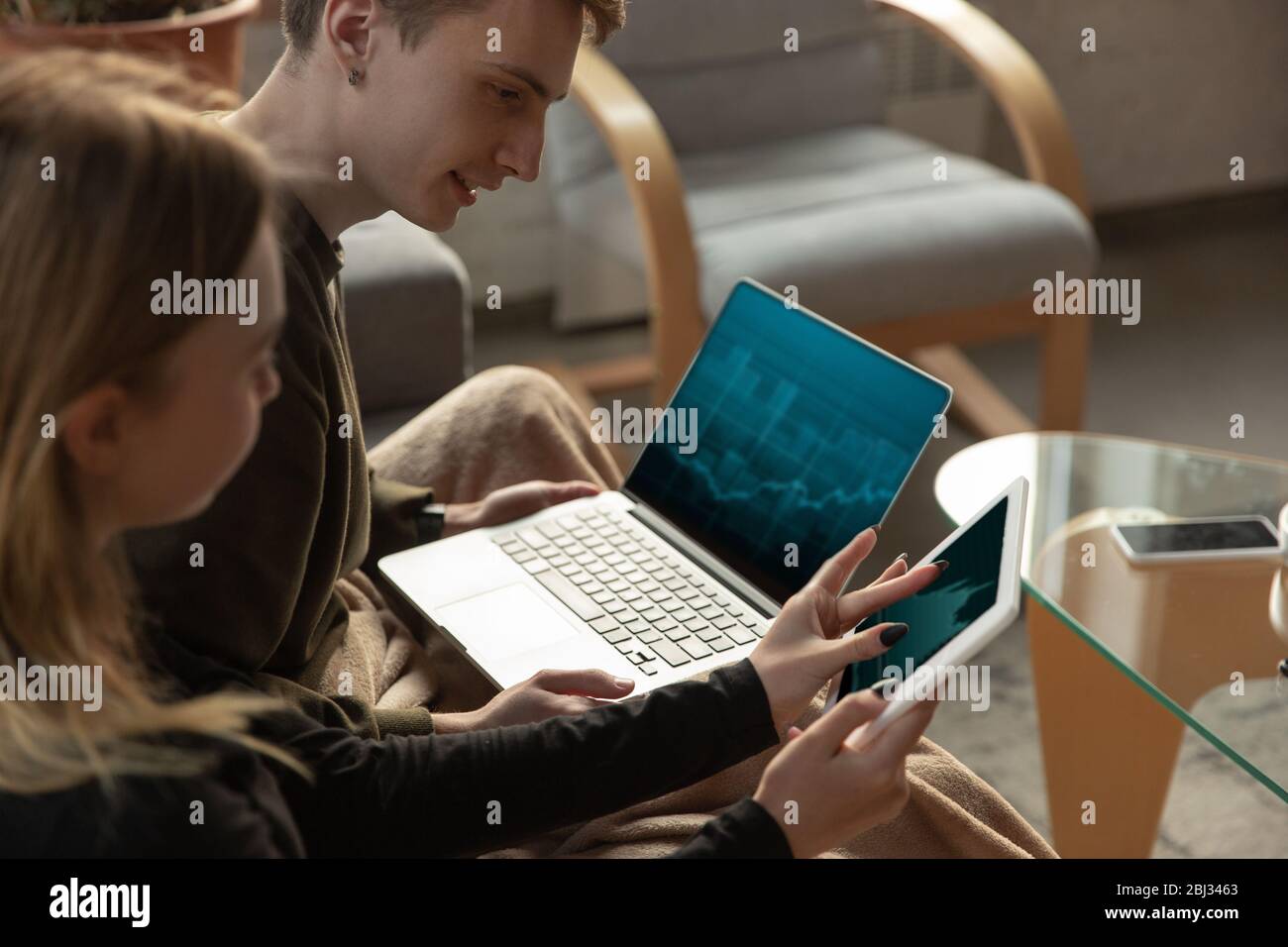 Attractive young couple using devices together, tablet, laptop ...