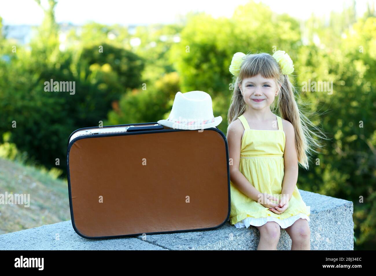 Little girl with suitcase outside Stock Photo - Alamy