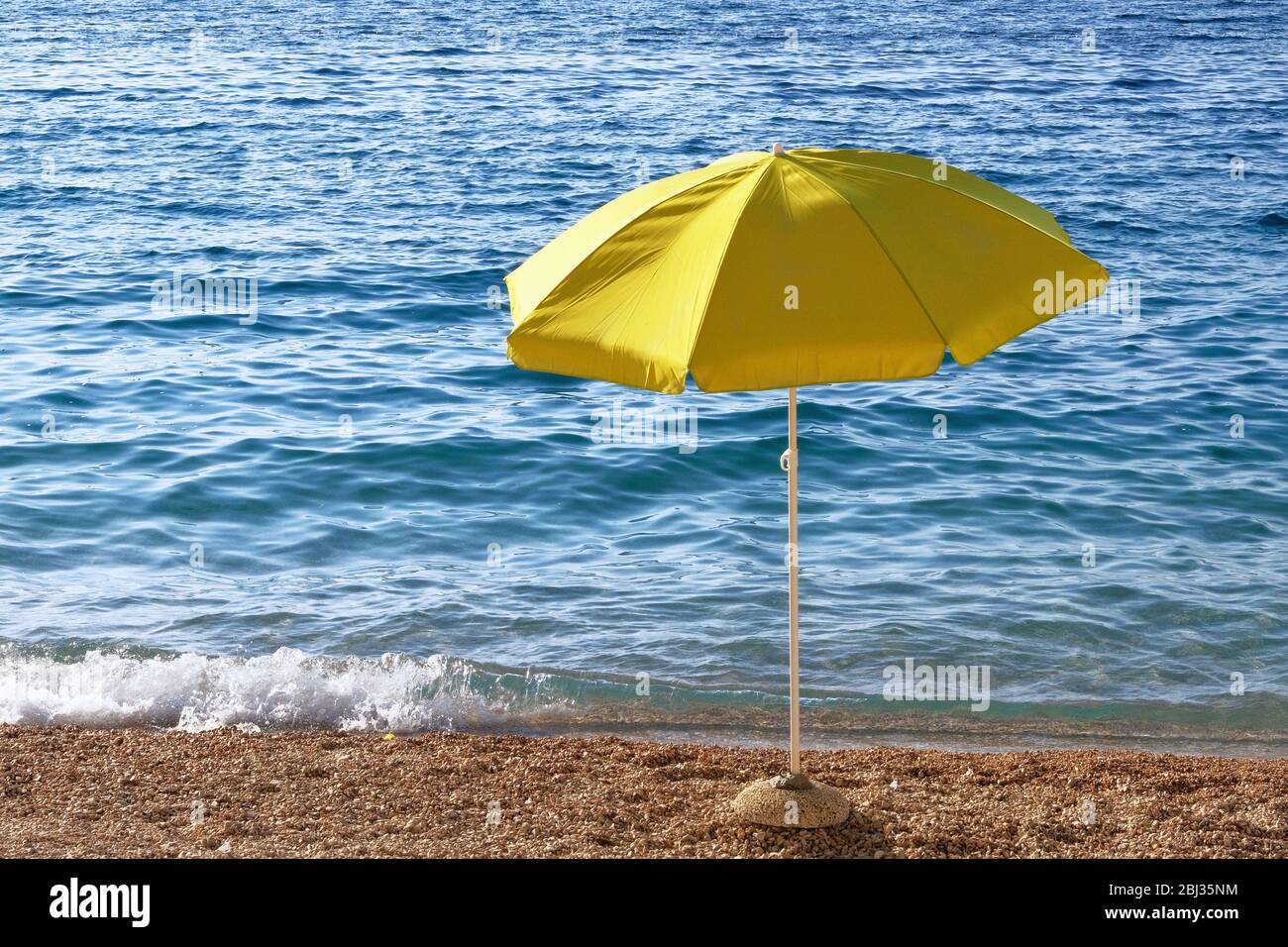 Yellow beach umbrella on summer coast. Sea beach with sun umbrella is ...