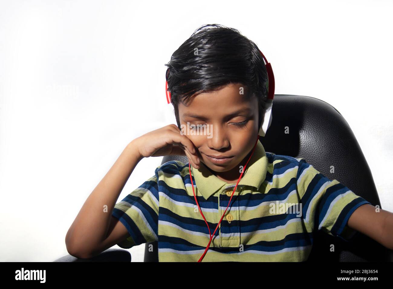 Boy with headphone sitting on Chair enjoying music Stock Photo - Alamy
