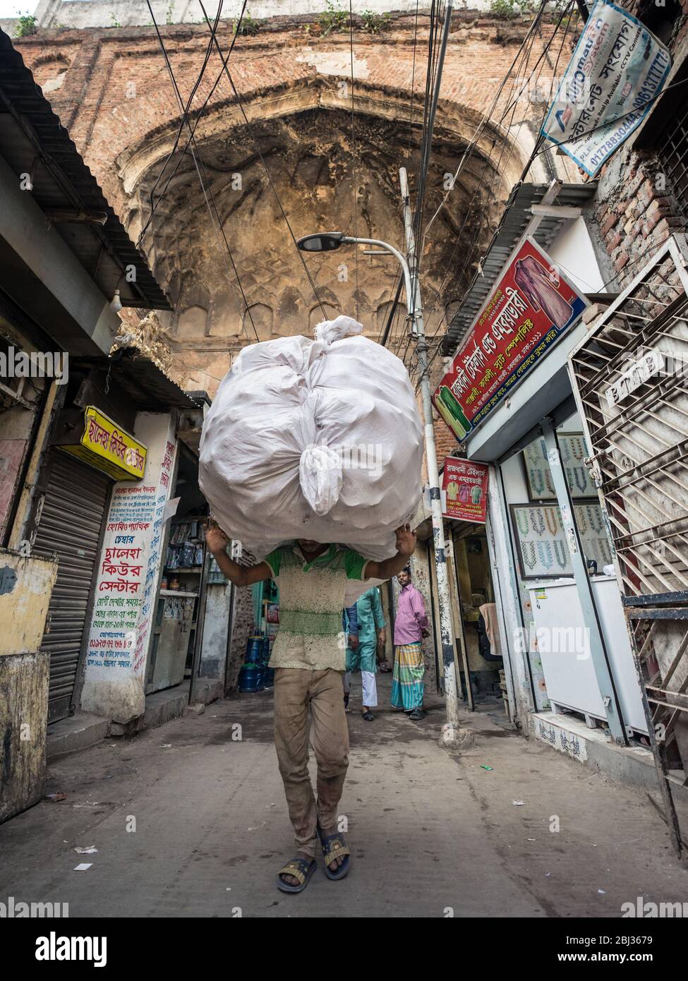 Dhaka / Bangladesh - January 14, 2019: Man carrying huge heavy burden ...