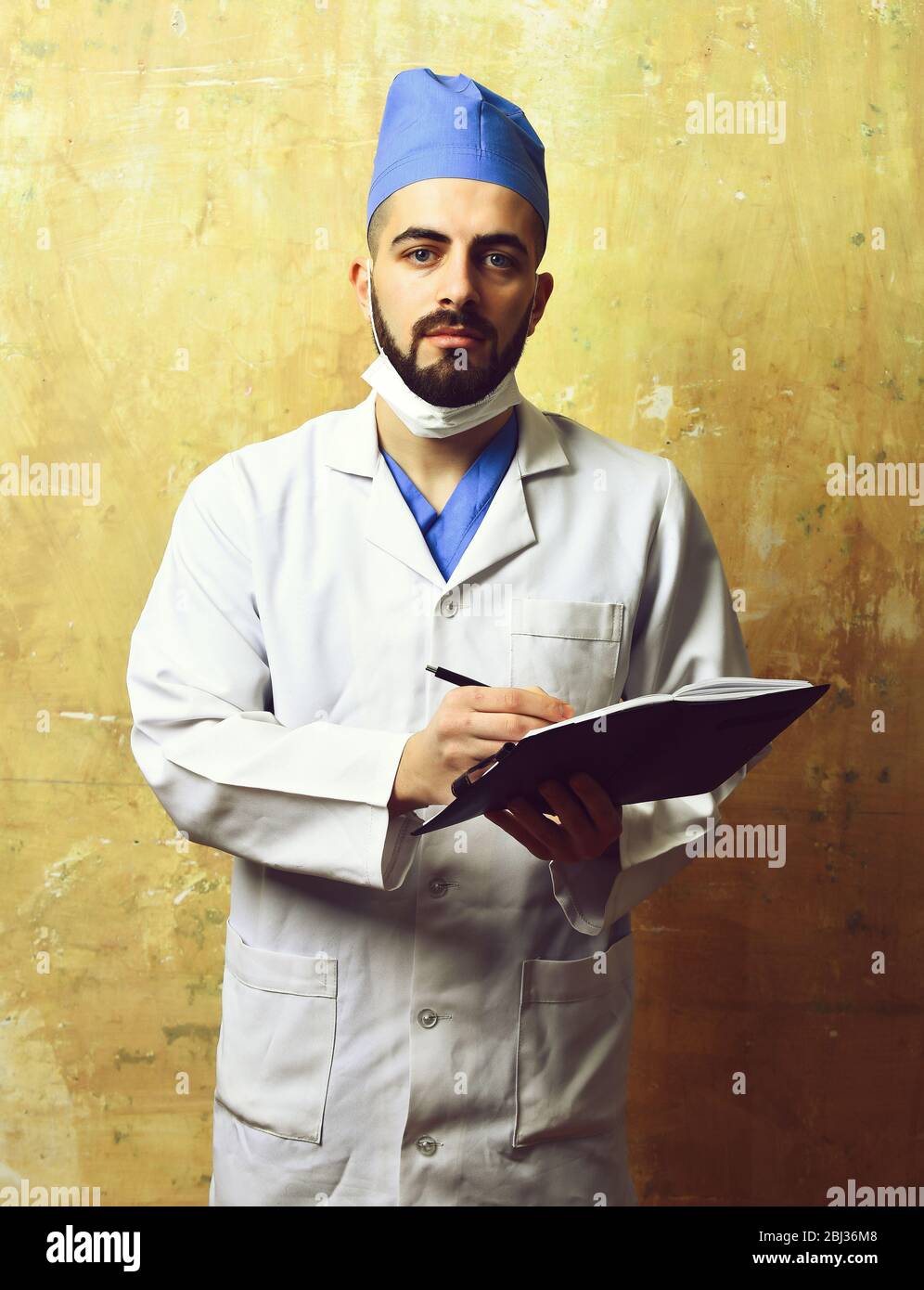 Surgeon with beard and tired face expression in white coat and blue ...