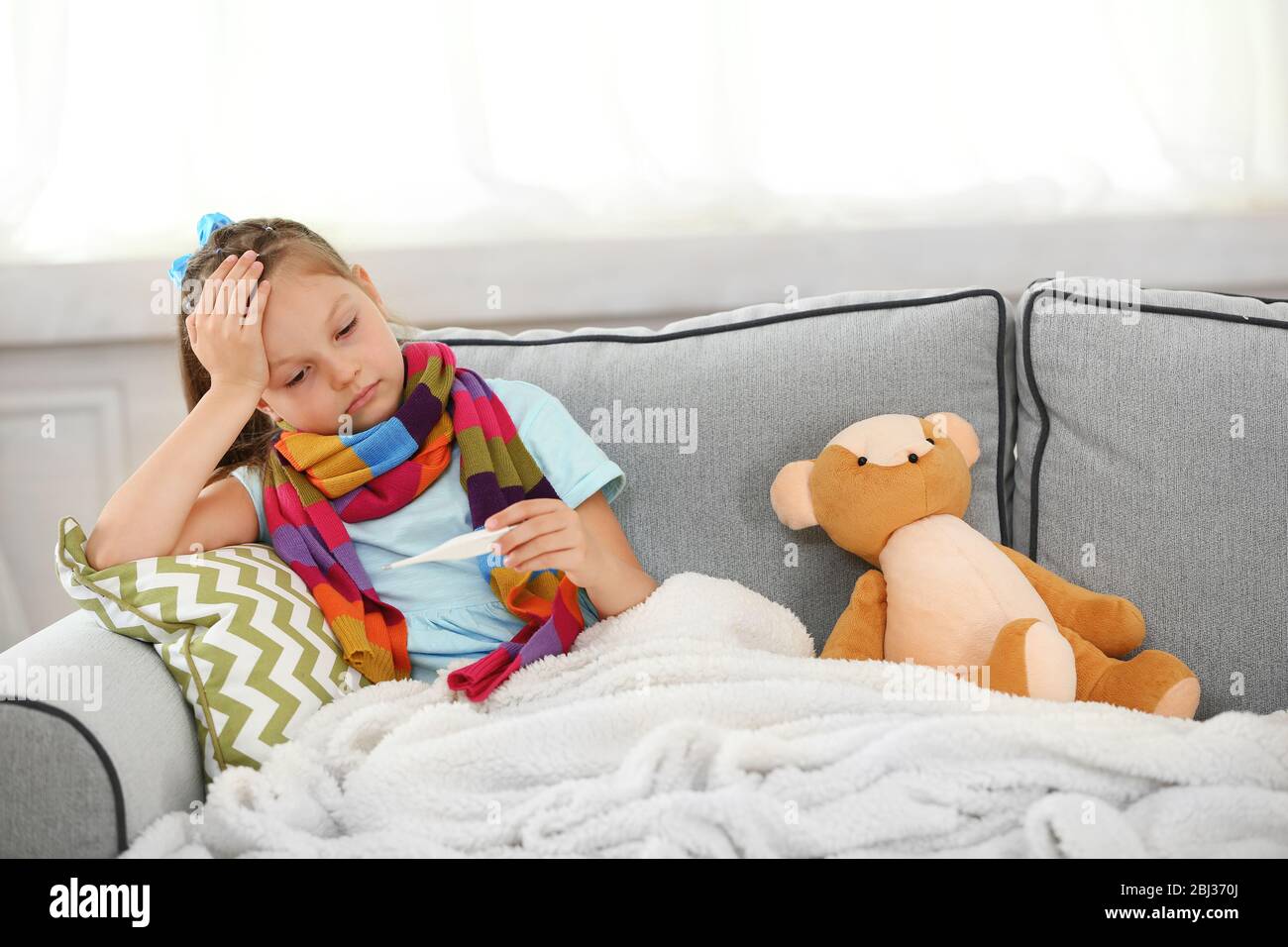 Sick girl with cold sitting on sofa Stock Photo - Alamy