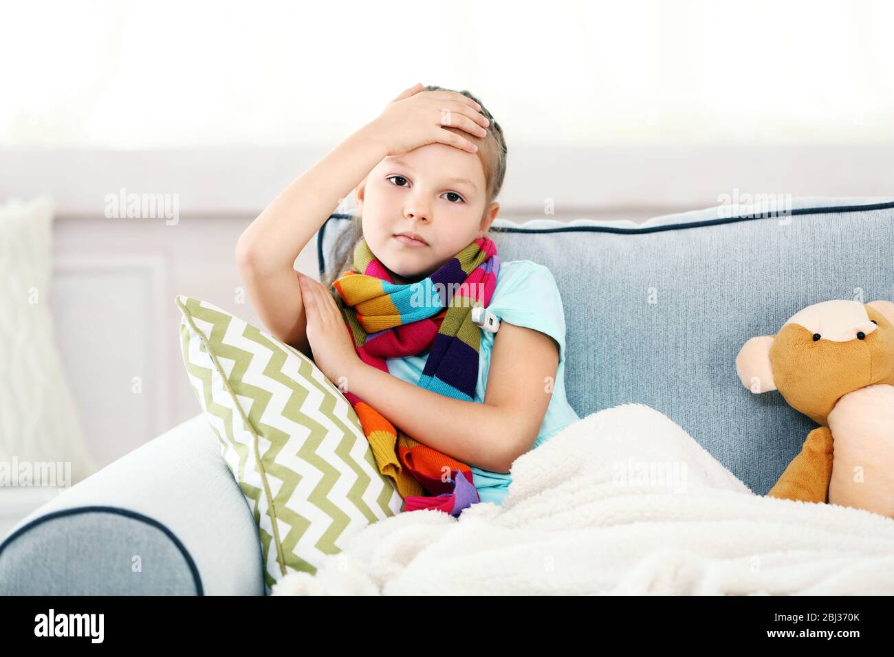 Sick girl with cold sitting on sofa Stock Photo - Alamy