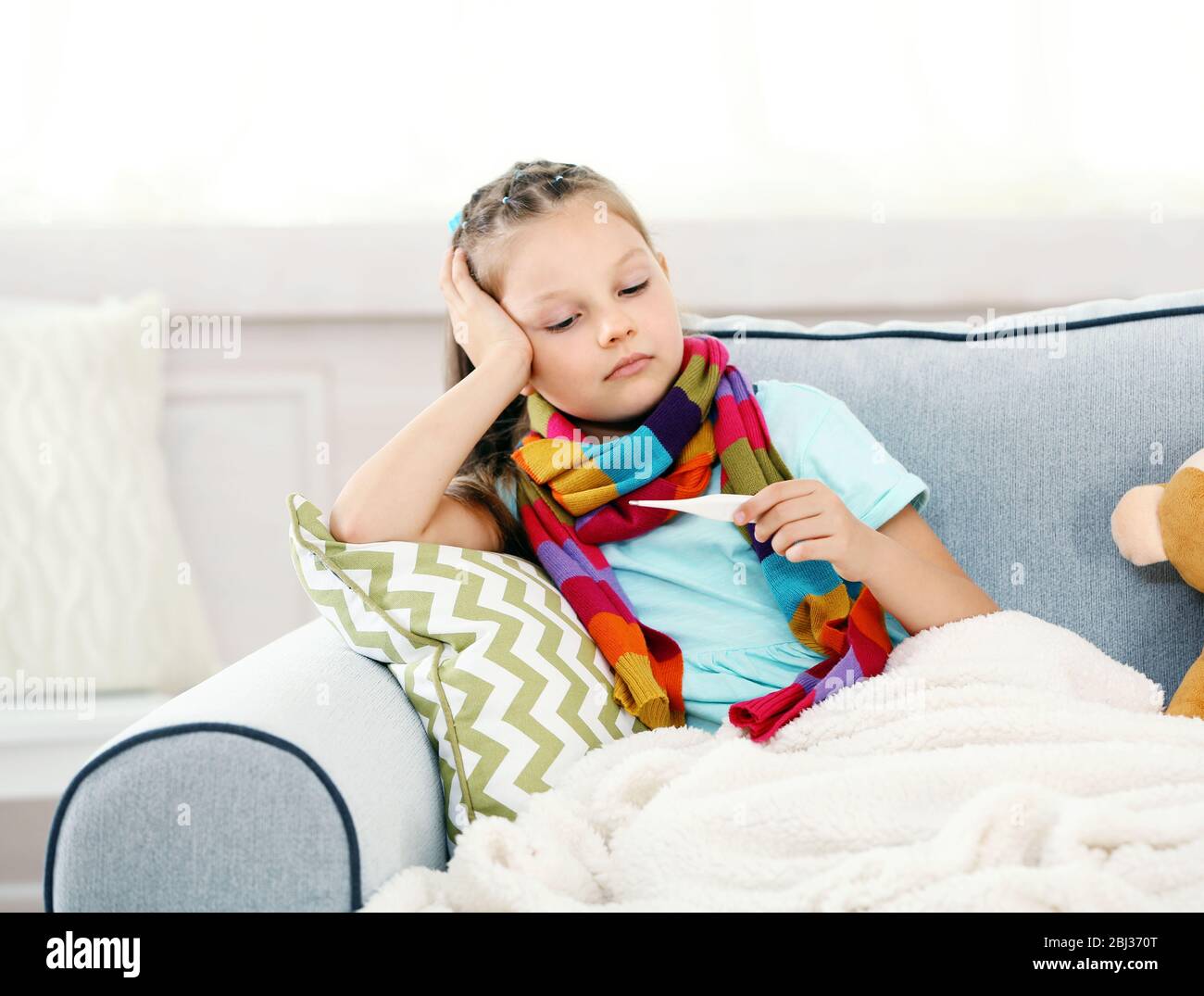 Sick girl with cold sitting on sofa Stock Photo - Alamy