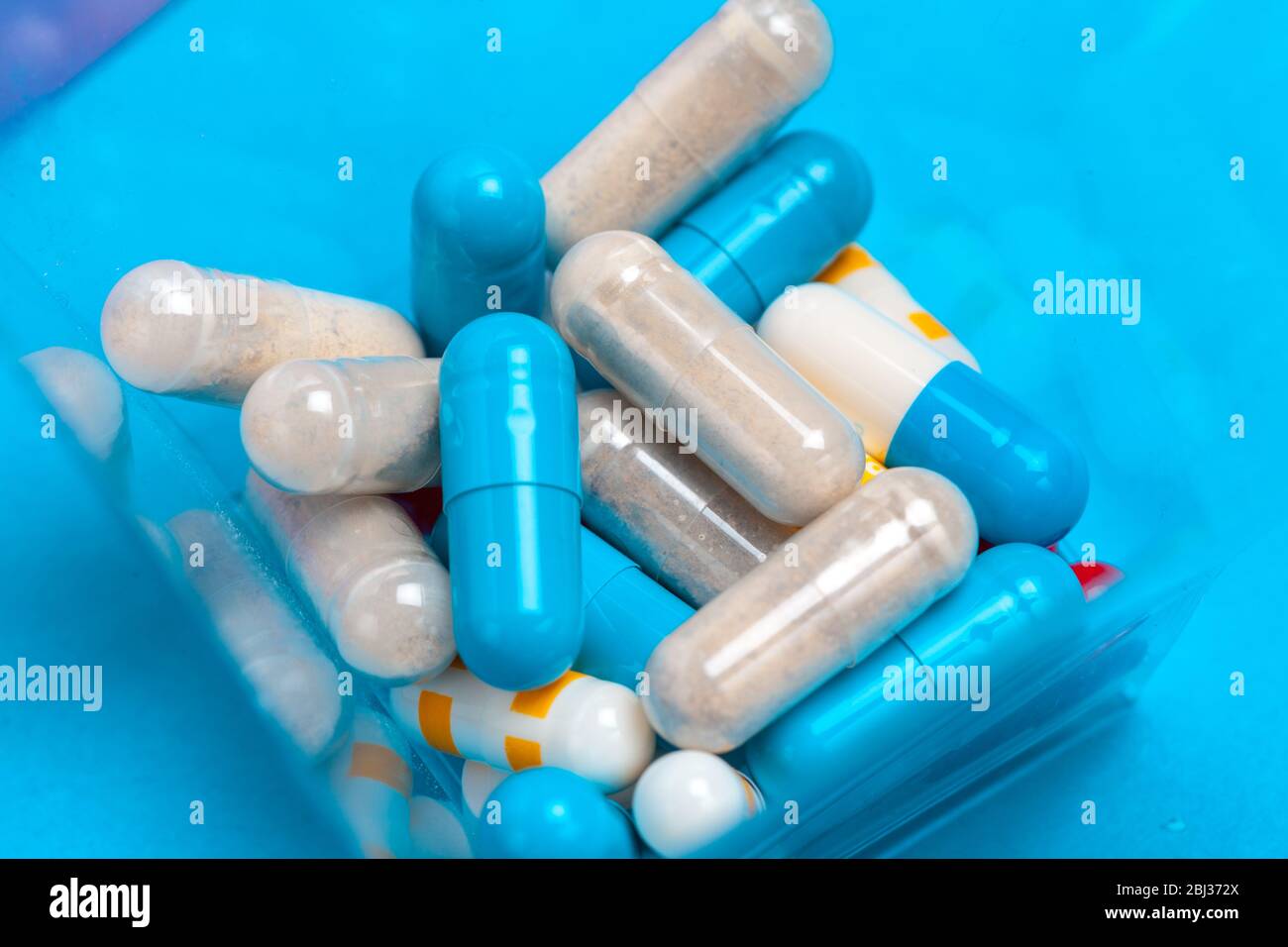 set of multi-colored tablets and capsules on a blue background Stock ...