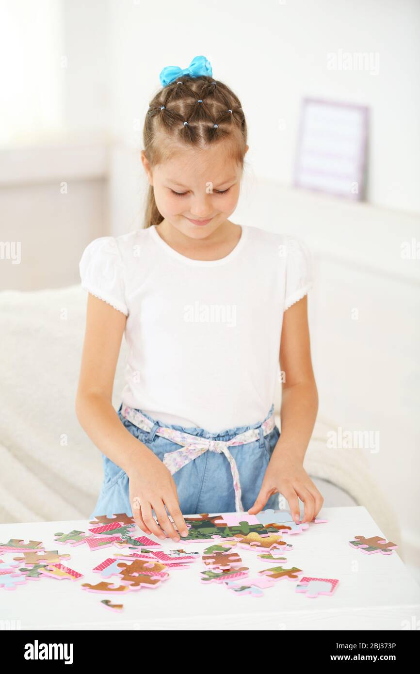 Cute little girl playing with puzzles on home interior background Stock ...
