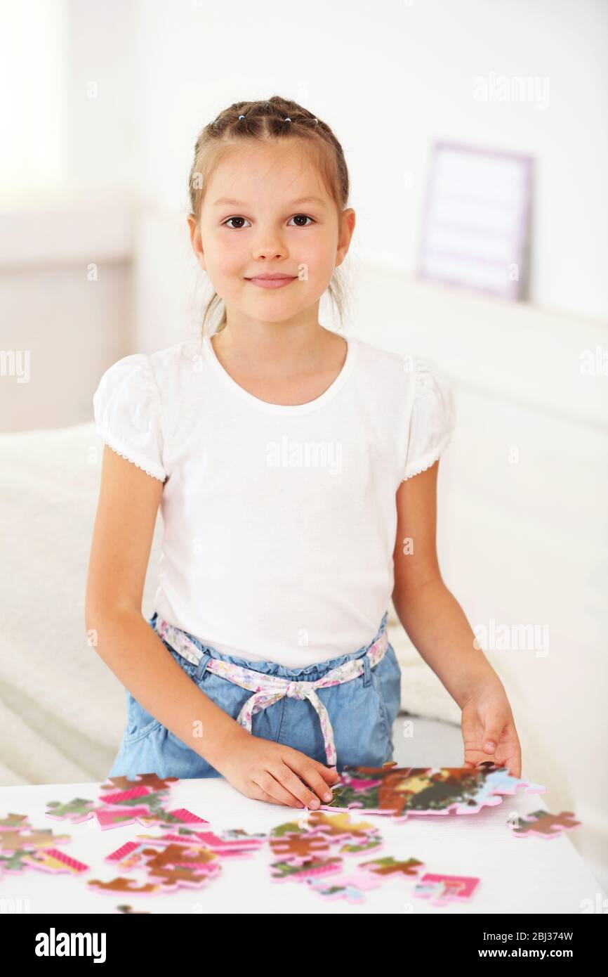 Cute little girl playing with puzzles on home interior background Stock ...