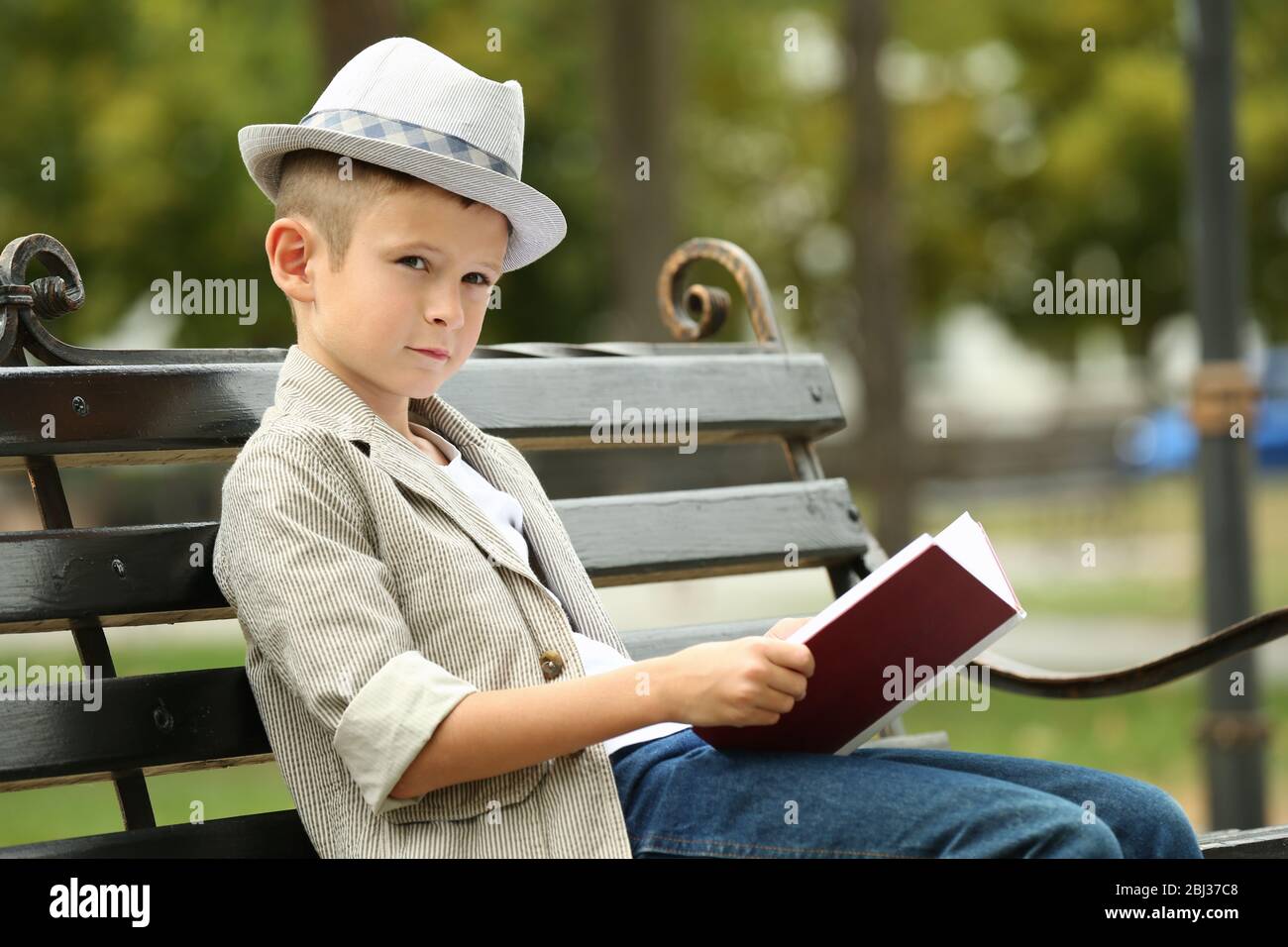 Little boy reading book on bench in the park Stock Photo - Alamy