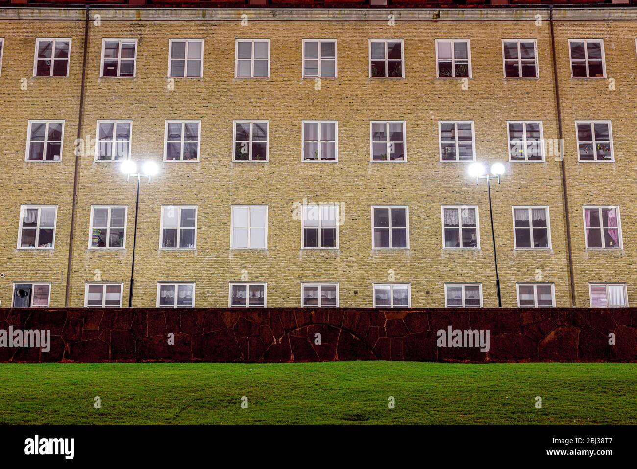 Windows of a yellow brick school building at night lit by street lamps ...