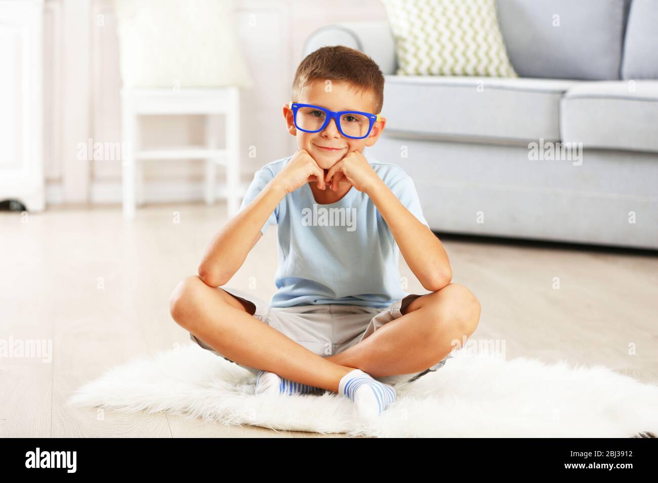 Little boy sitting on carpet, on home interior background Stock Photo ...