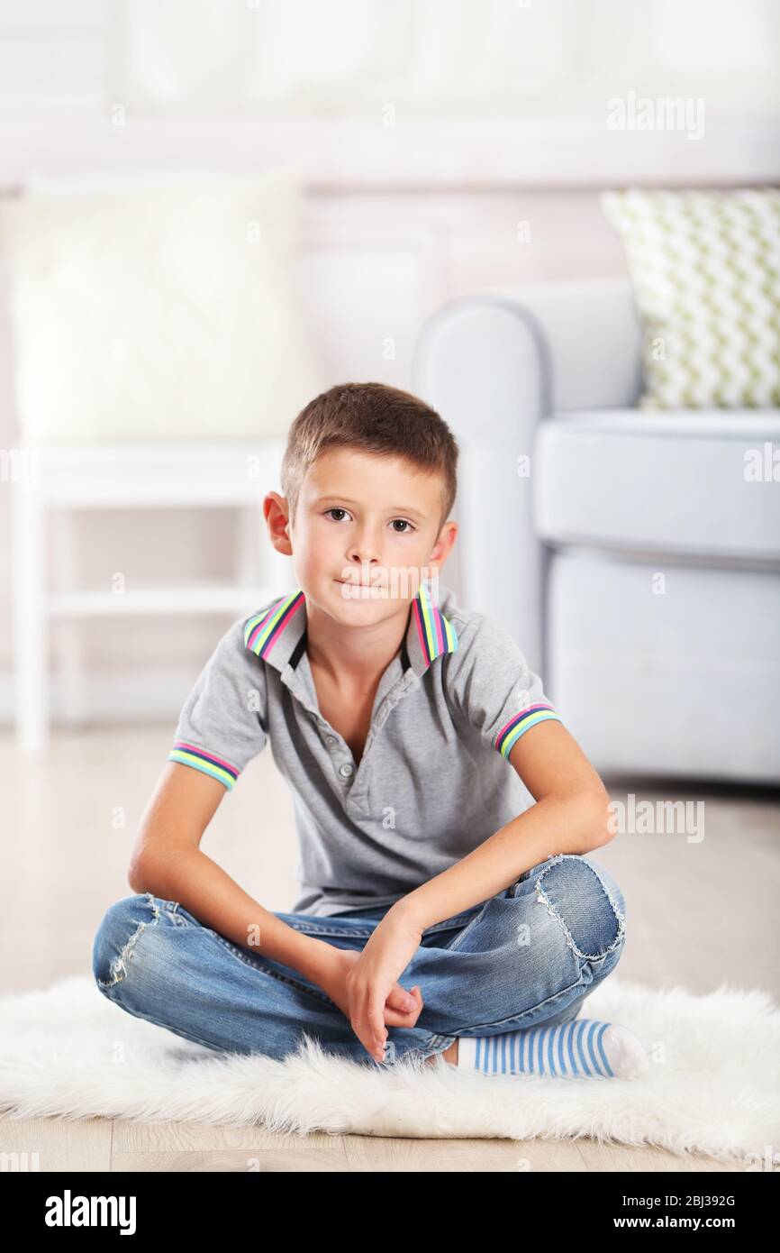 Little boy sitting on carpet, on home interior background Stock Photo ...