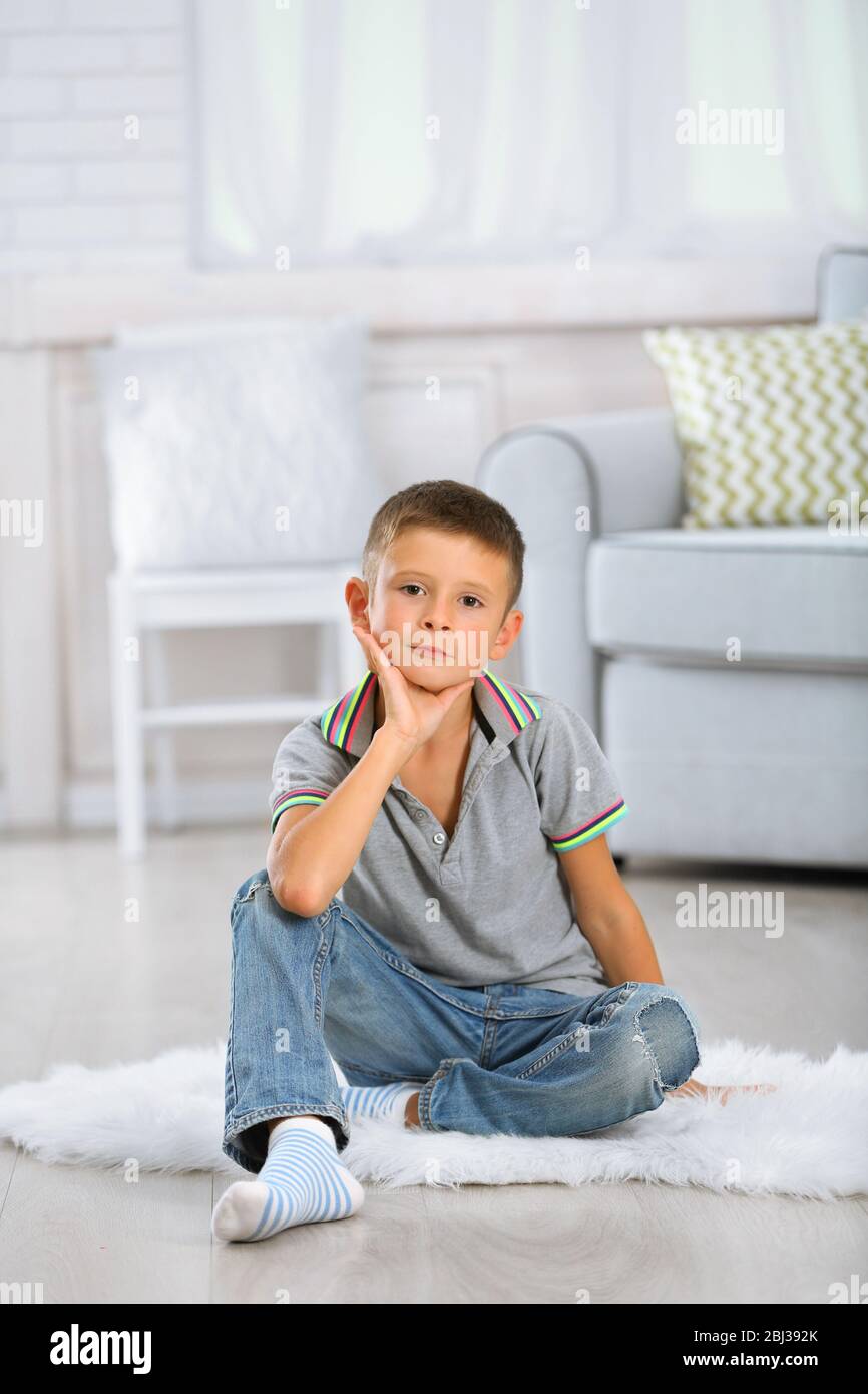 Little boy sitting on carpet, on home interior background Stock Photo ...