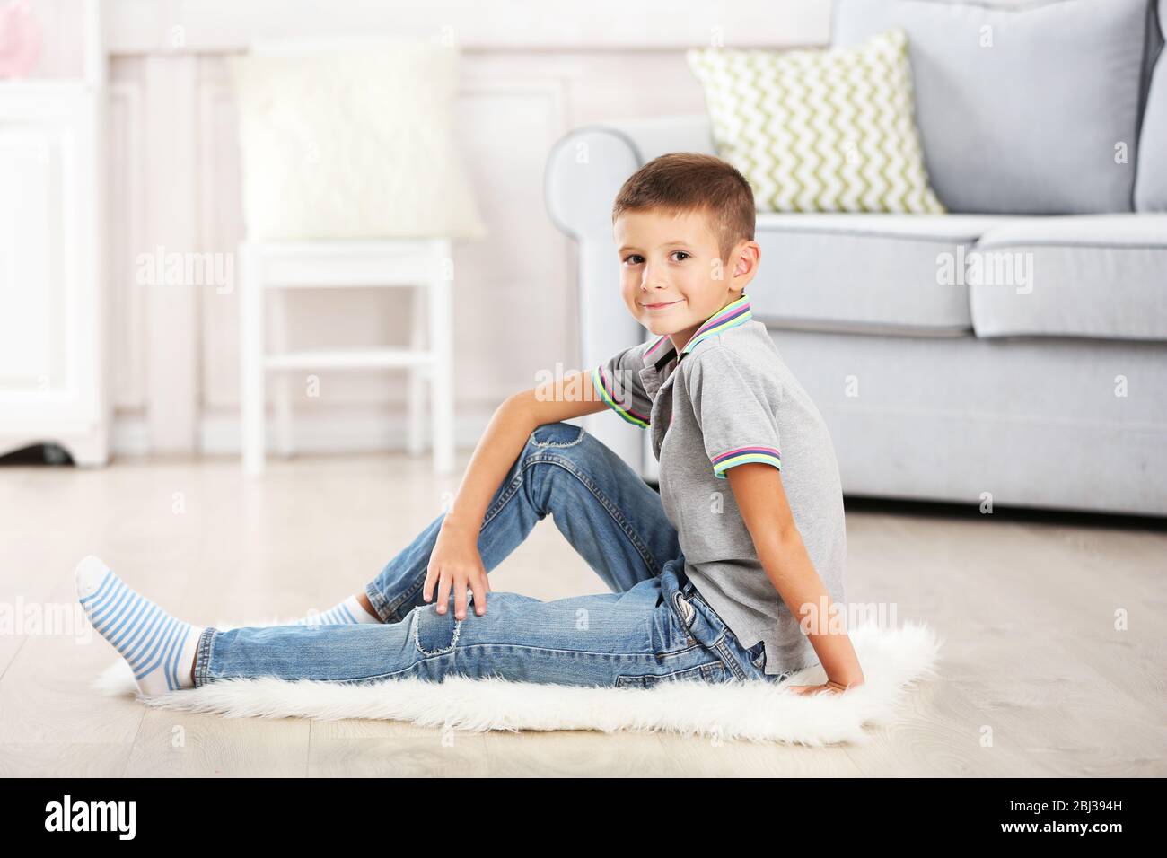 Little boy sitting on carpet, on home interior background Stock Photo ...