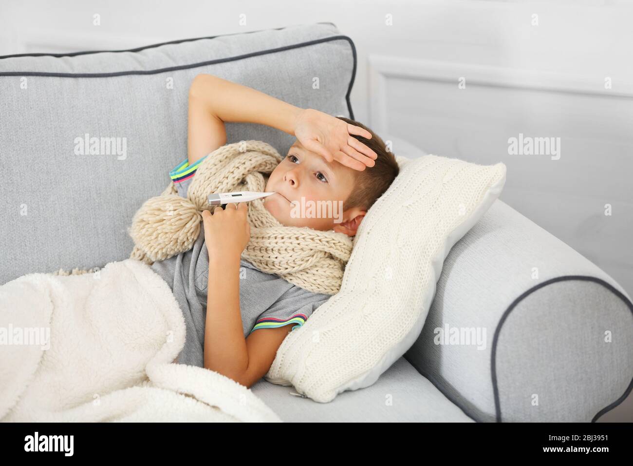 Sick boy with cold sitting on sofa Stock Photo - Alamy