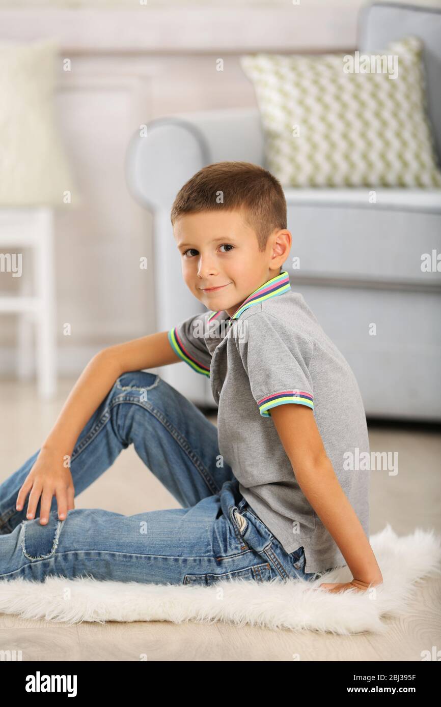 Little boy sitting on carpet, on home interior background Stock Photo ...