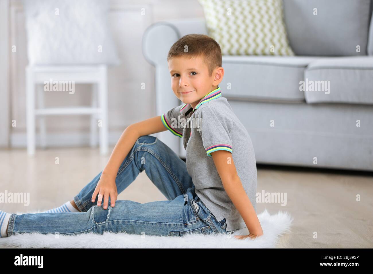 Little boy sitting on carpet, on home interior background Stock Photo ...