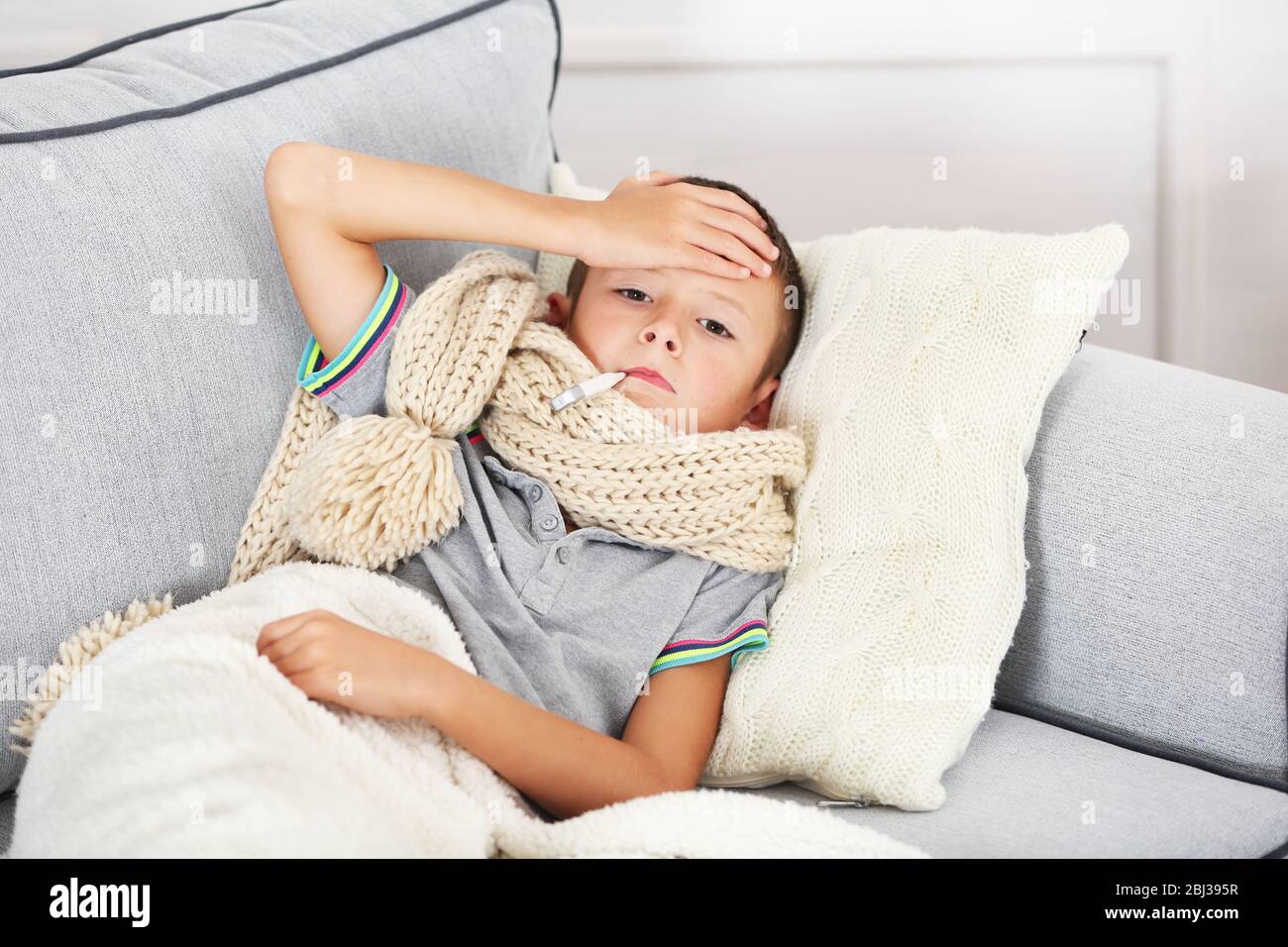 Sick boy with cold sitting on sofa Stock Photo - Alamy