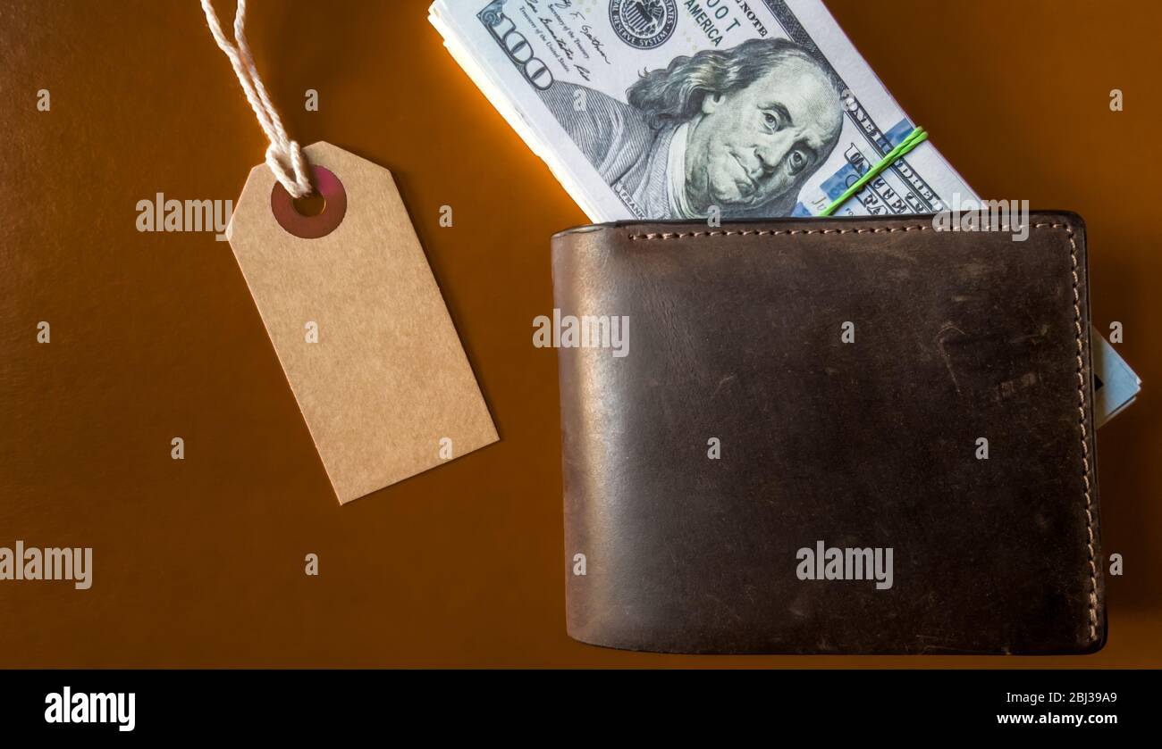 Many hundreds of dollars banknotes in a leather wallet with a brown tag ...