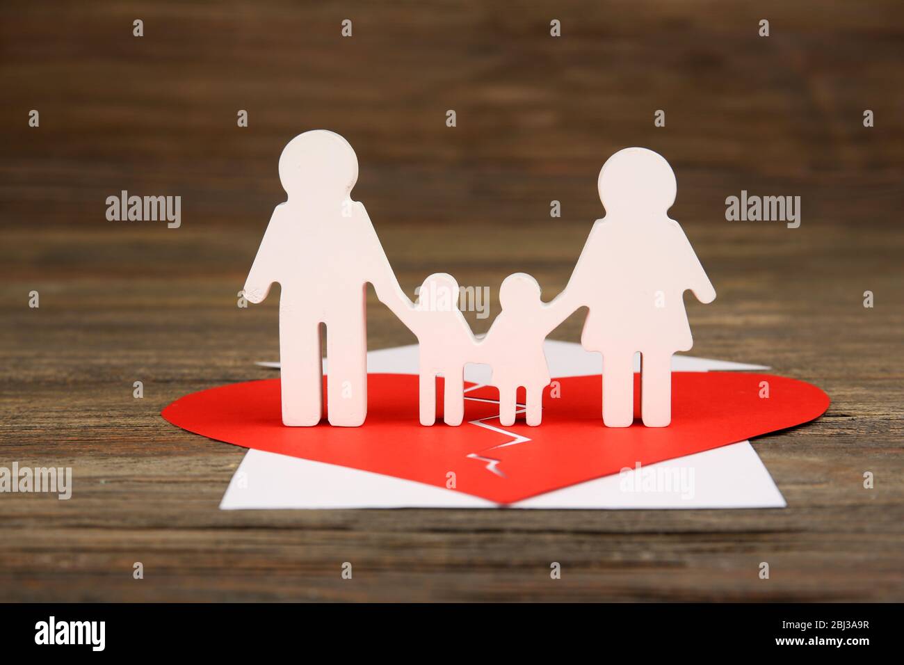 Cutout silhouette of a family split apart on a paper heart, divorce ...