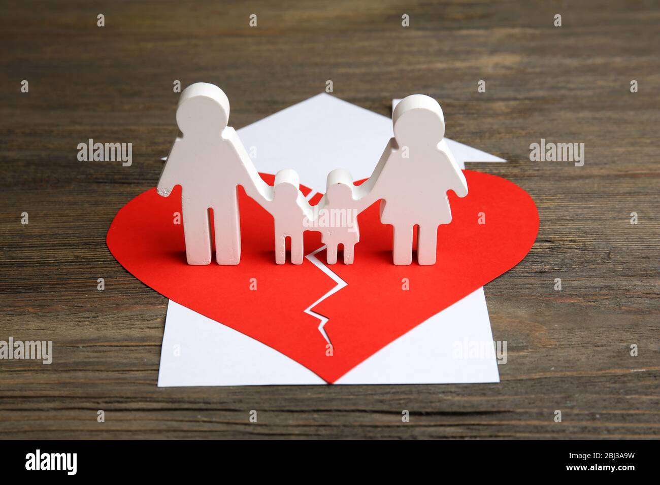 Cutout silhouette of a family split apart on a paper heart, divorce ...