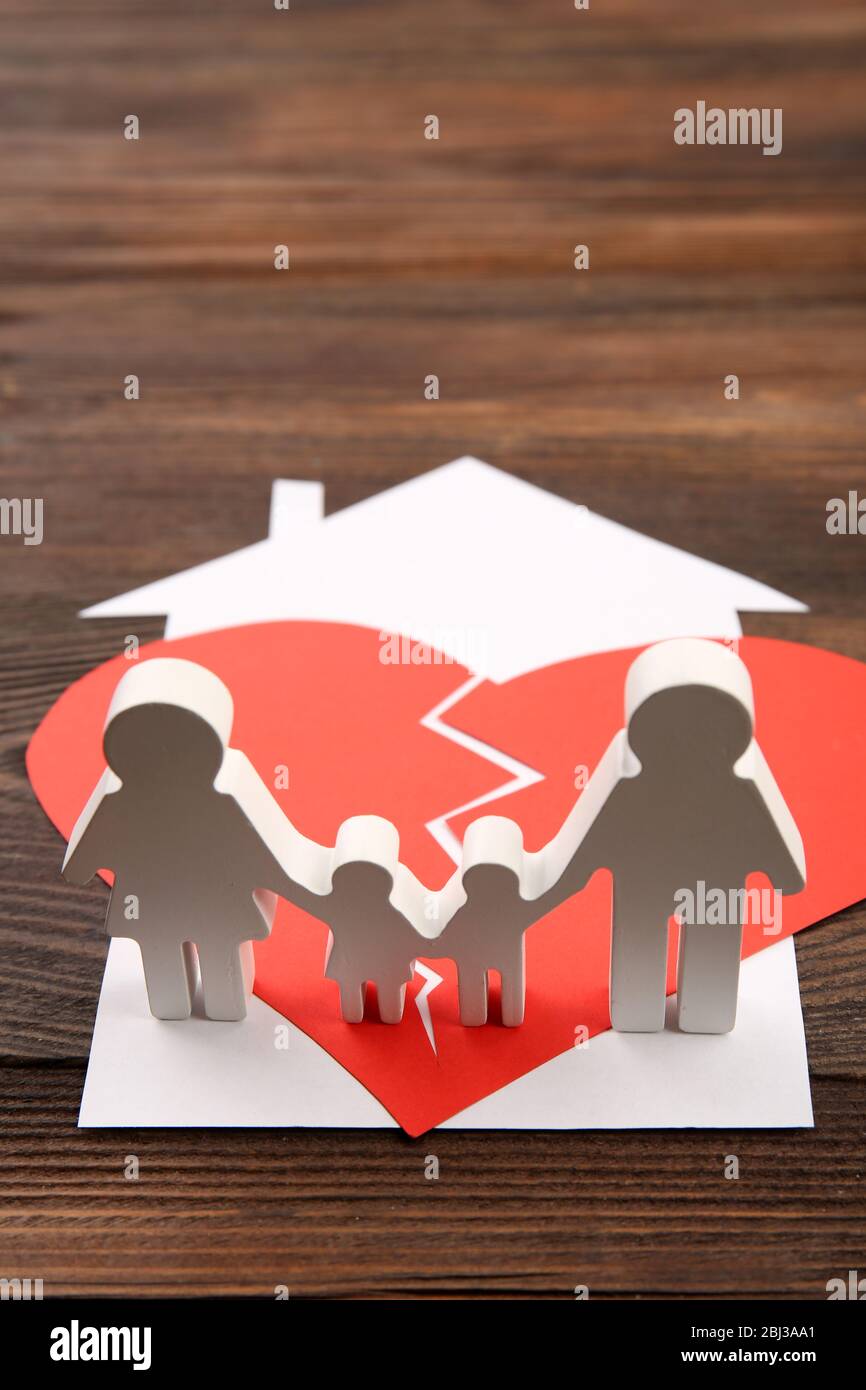 Paper cutout silhouette of a family split apart on a paper heart ...