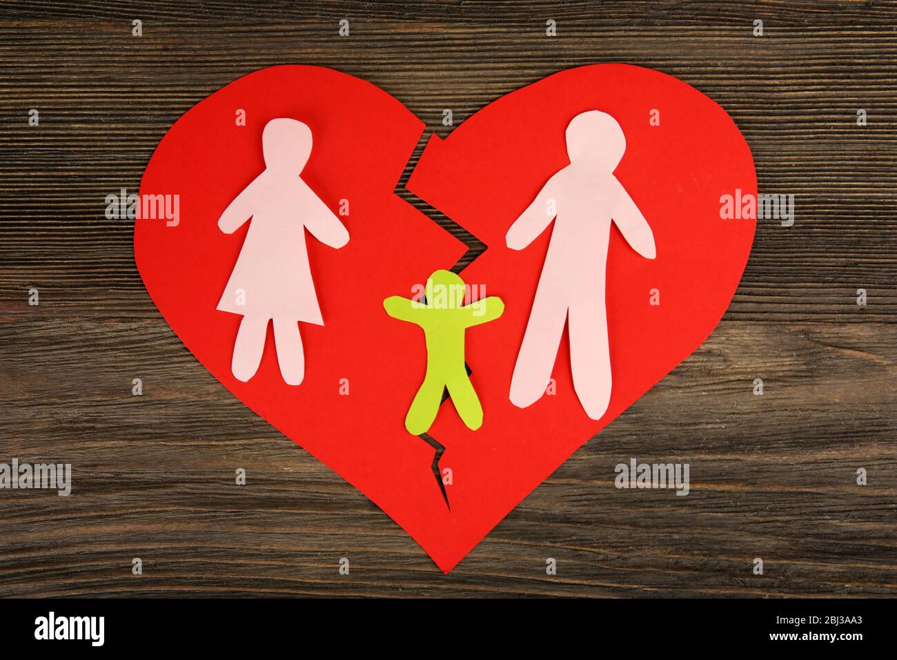 Paper cutout silhouette of a family split apart on a paper heart ...
