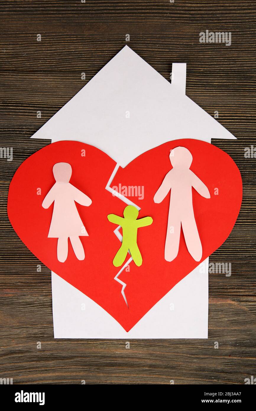 Paper cutout silhouette of a family split apart on a paper heart ...