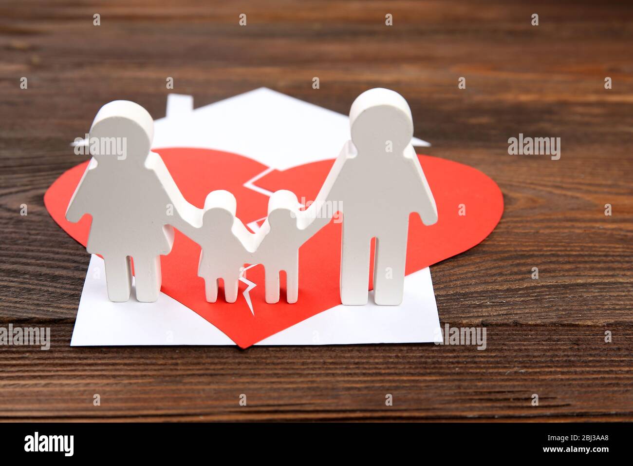 Paper cutout silhouette of a family split apart on a paper heart ...