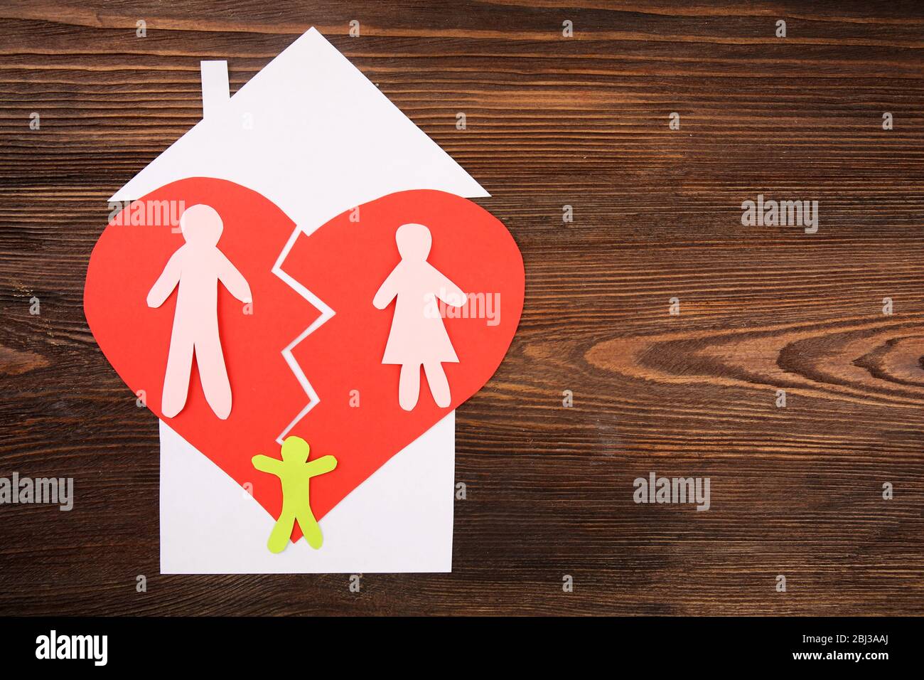 Paper cutout silhouette of a family split apart on a paper heart ...