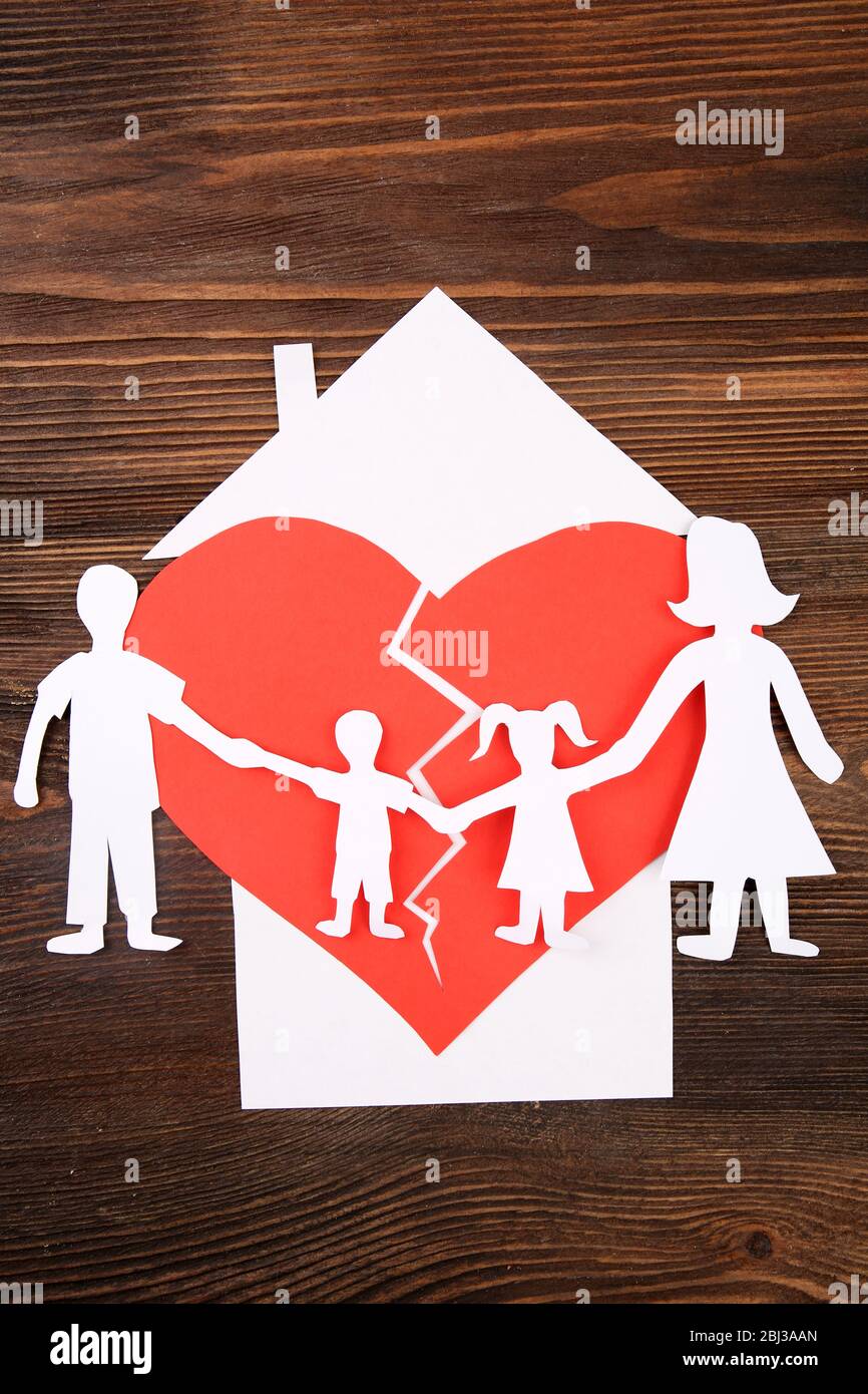 Paper cutout silhouette of a family split apart on a paper heart ...