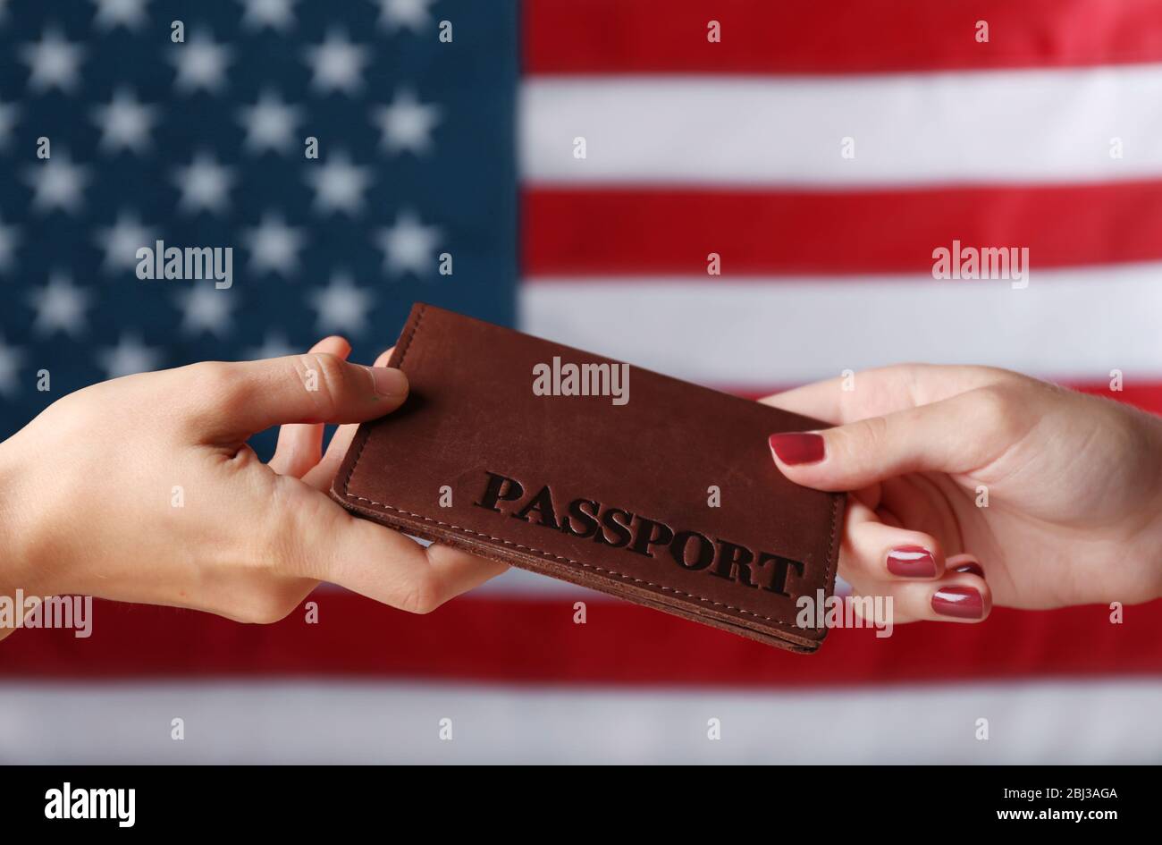 One hand giving the passport to another on American Flag background ...