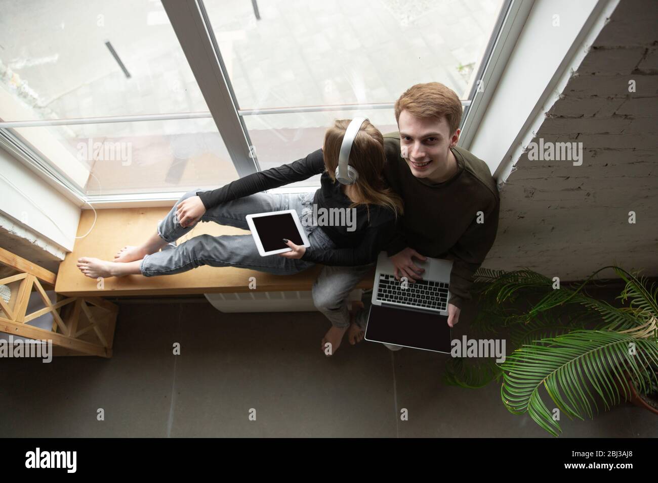 Attractive young couple using devices together, tablet, laptop ...