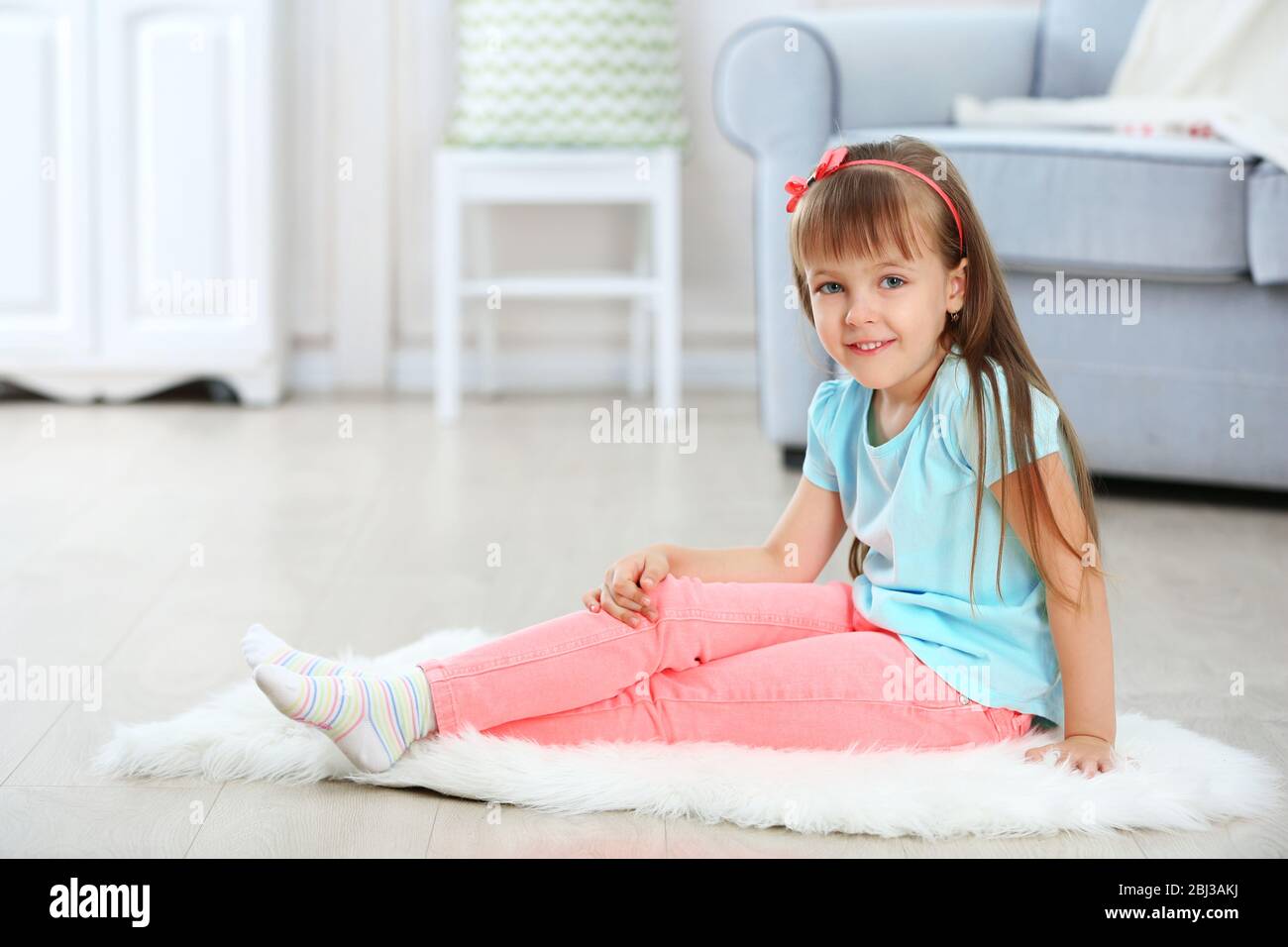 Little cute girl sitting on carpet, on home interior background Stock ...